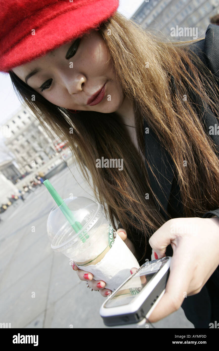 Young Chinese girl with mobilephone and milkshake in Trafalgar Square ...