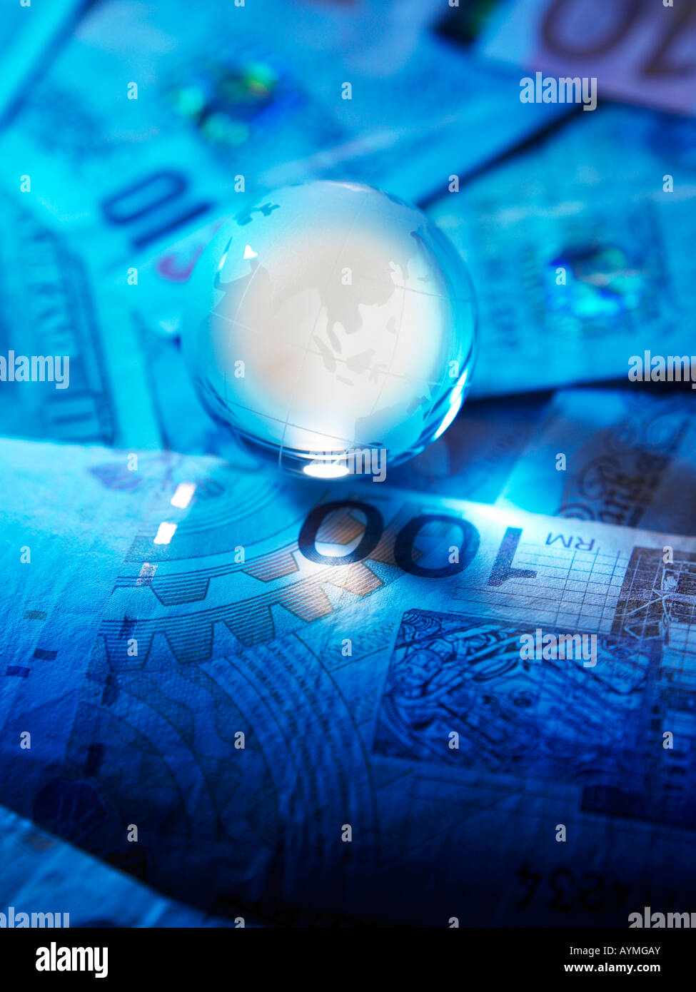 Variety of currencies in blue light with glass globe Stock Photo - Alamy