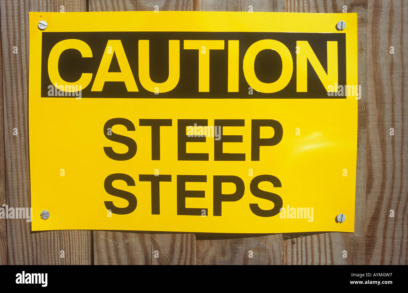 Close up of yellow and black plastic sign screwed onto new wooden fence ...