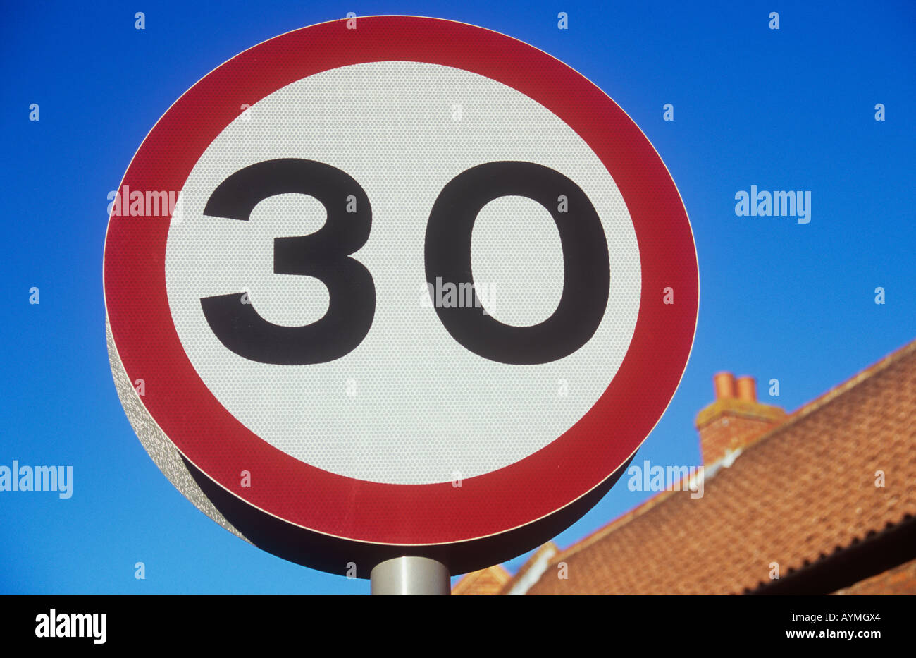 Close up of circular speed limit road sign stating 30 against blue sky ...