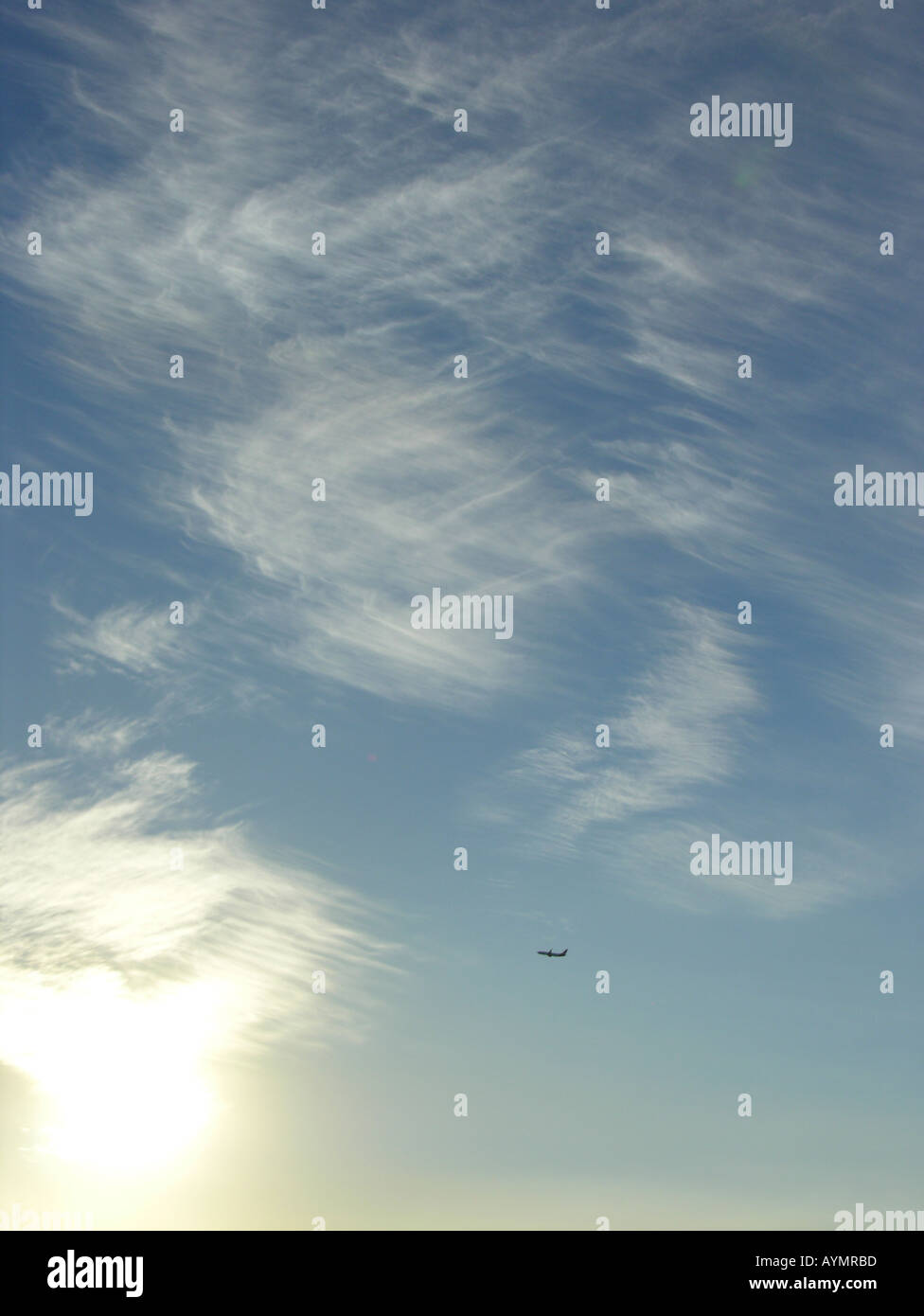 Jet plane flying under white cloud streaks Stock Photo - Alamy