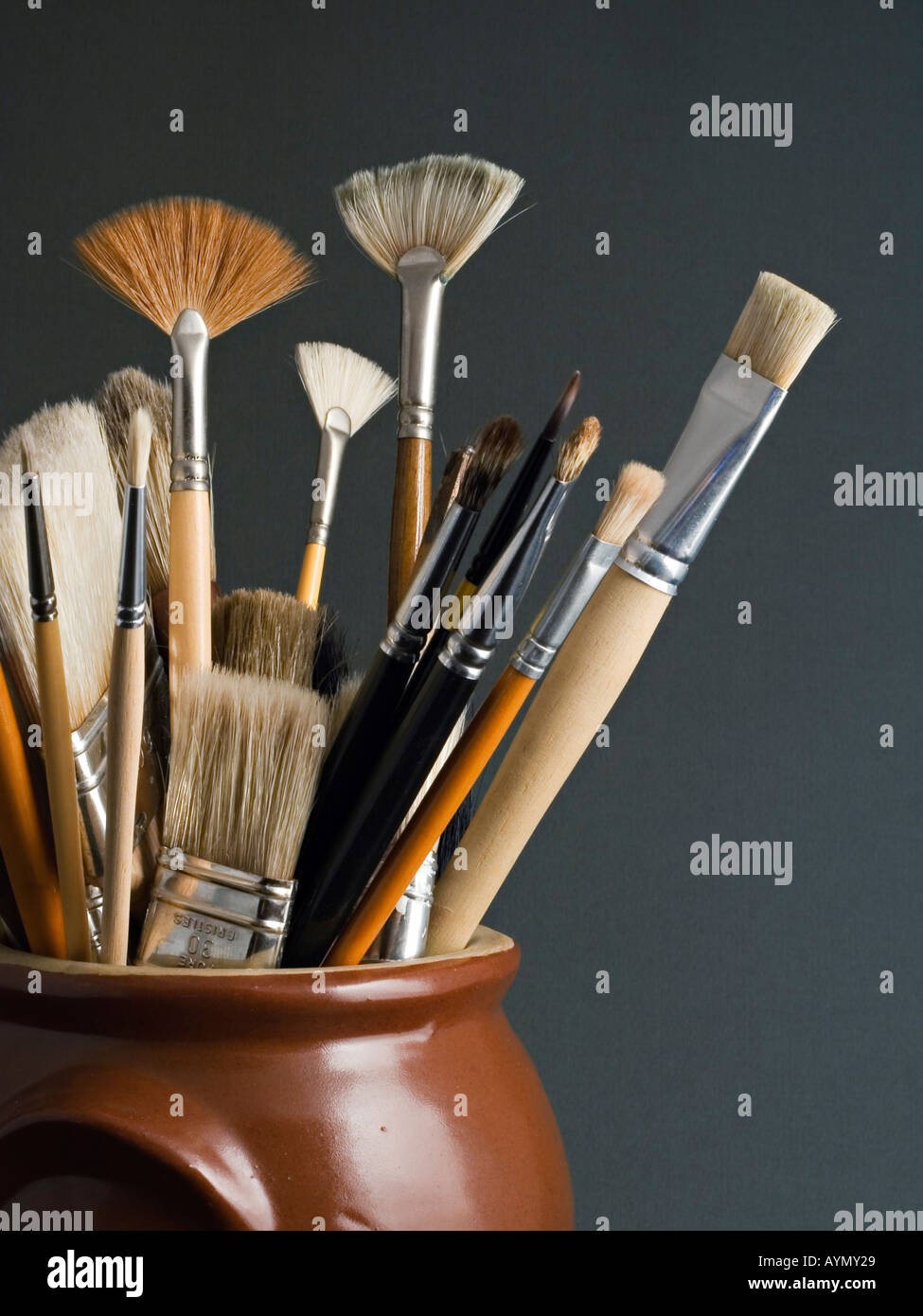 Artist brushes in a pot on a dark background Stock Photo - Alamy