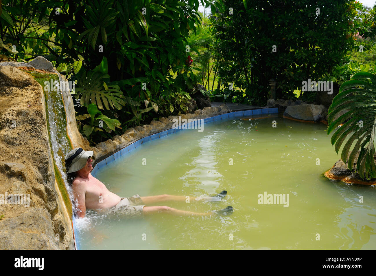 Tourist soaking in hot mineral springs waterfall pool at Paraiso resort ...