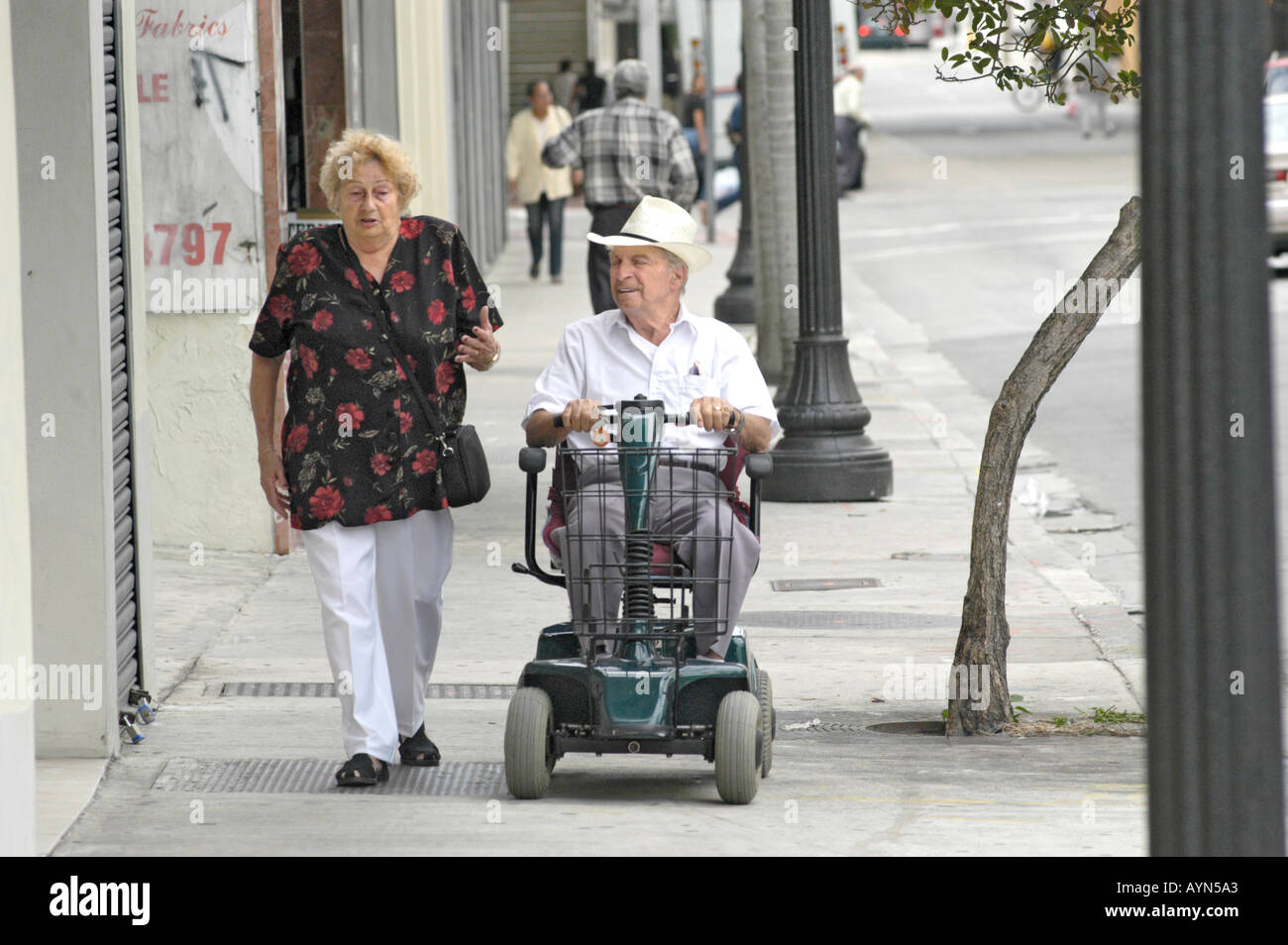 Two people on public street one in wheeled chair Stock Photo - Alamy