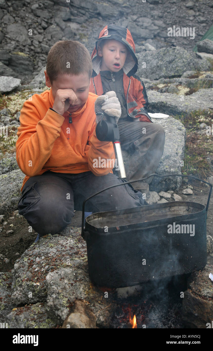 Two boys cooking on the fire during a trekking in the Khibiny mountains ...