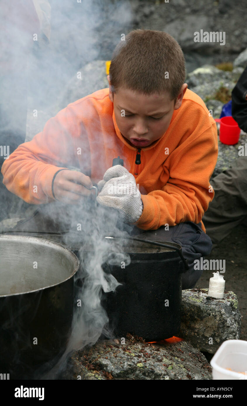 Young boy cooking on the fire during a trekking in the Khibiny ...