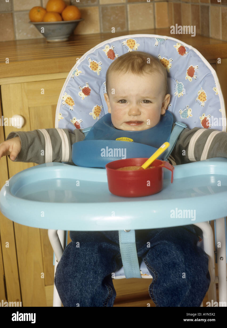 Toddler sitting down in a highchair refusing his food Stock Photo - Alamy