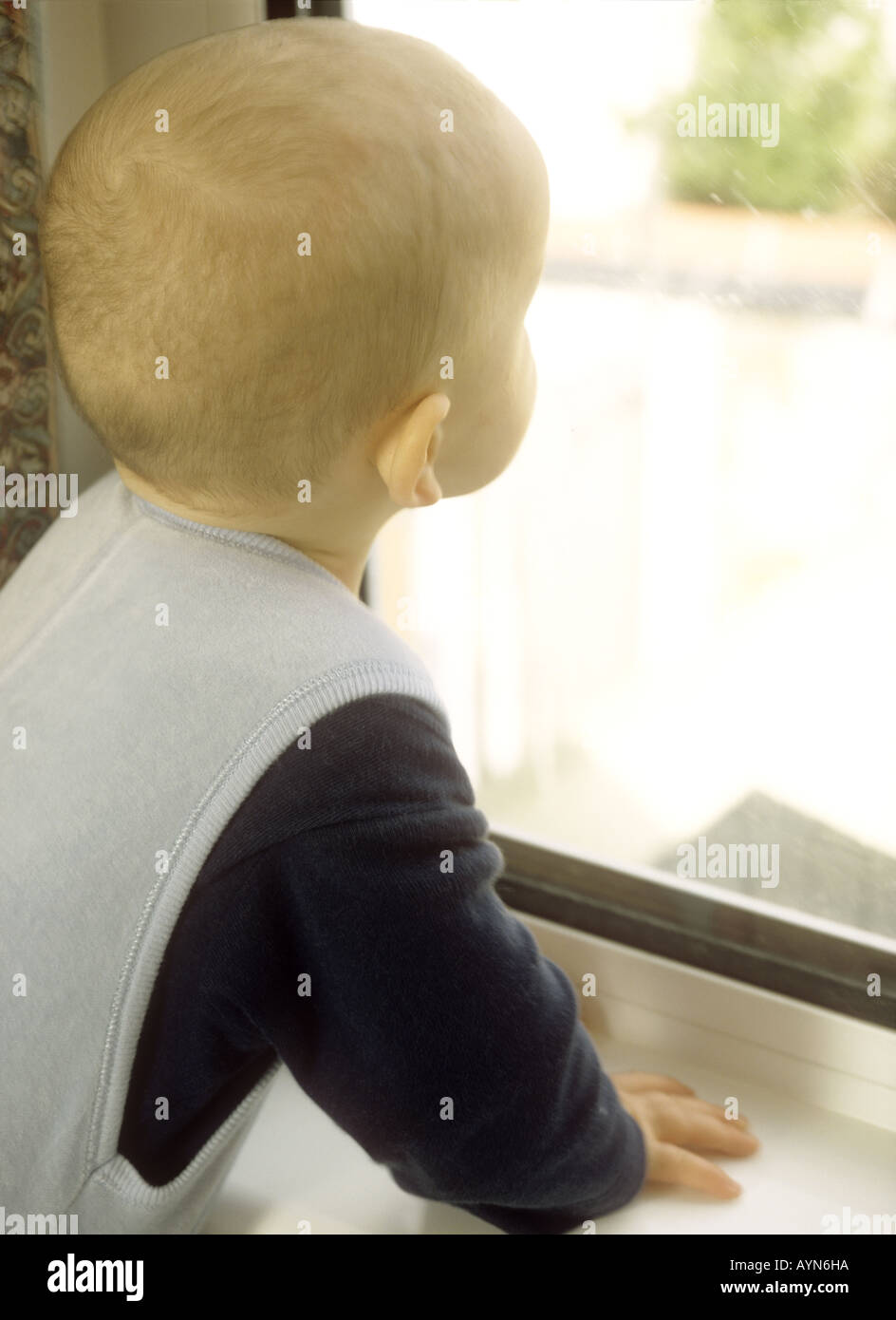 Baby boy looking out of window Stock Photo - Alamy