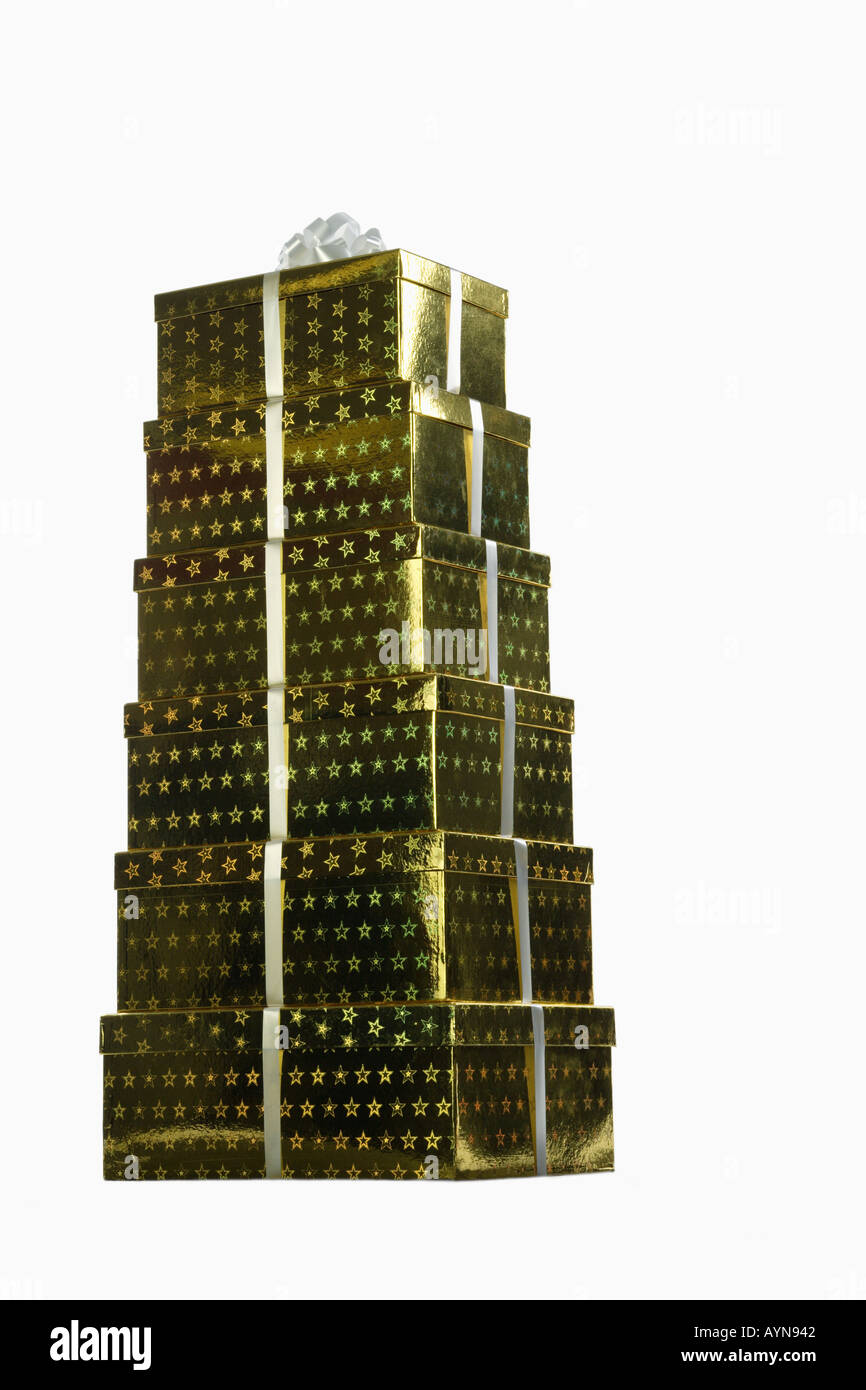 Still life of a stack of gold wrapped presents silhouetted on white ...