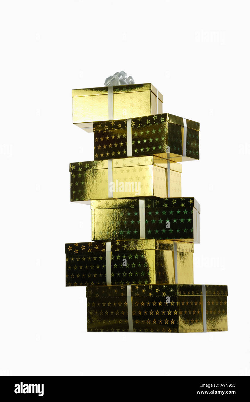 Still life of a stack of gold wrapped presents silhouetted on white ...