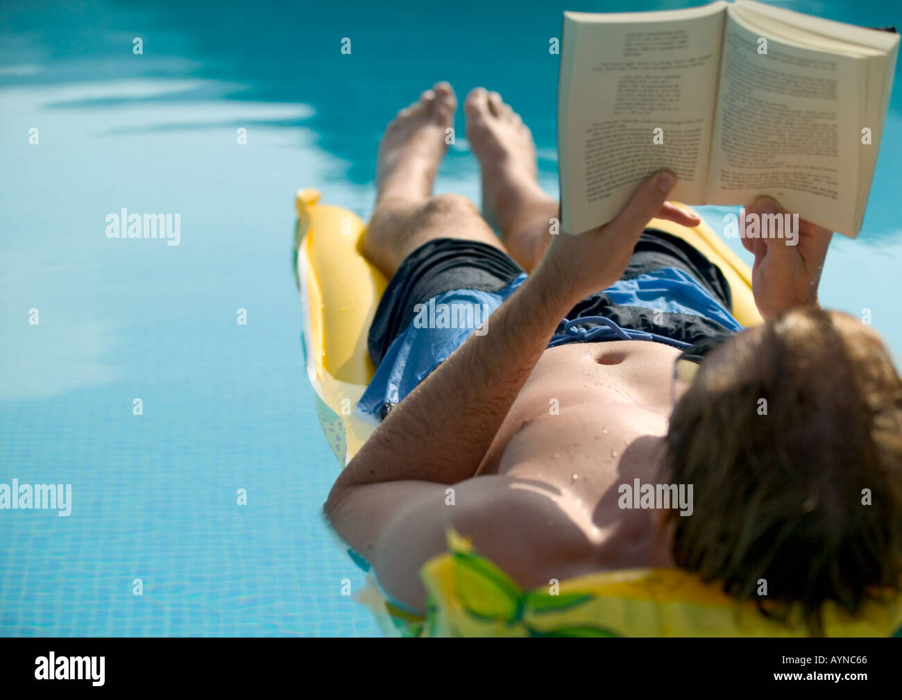 man reading book on lio in swimming pool Stock Photo - Alamy