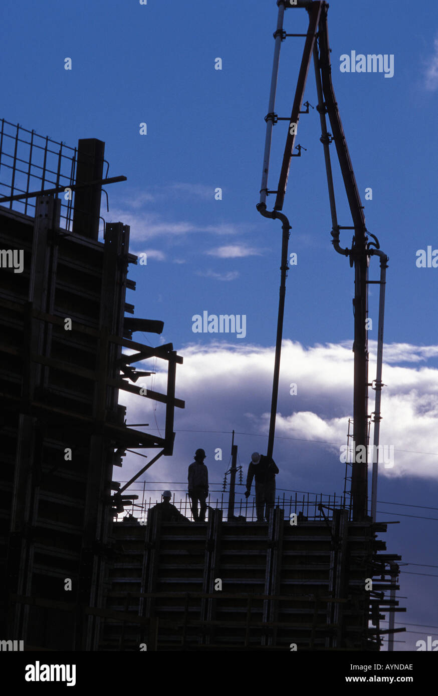 Construction workers on building site using concrete pumping equipment ...
