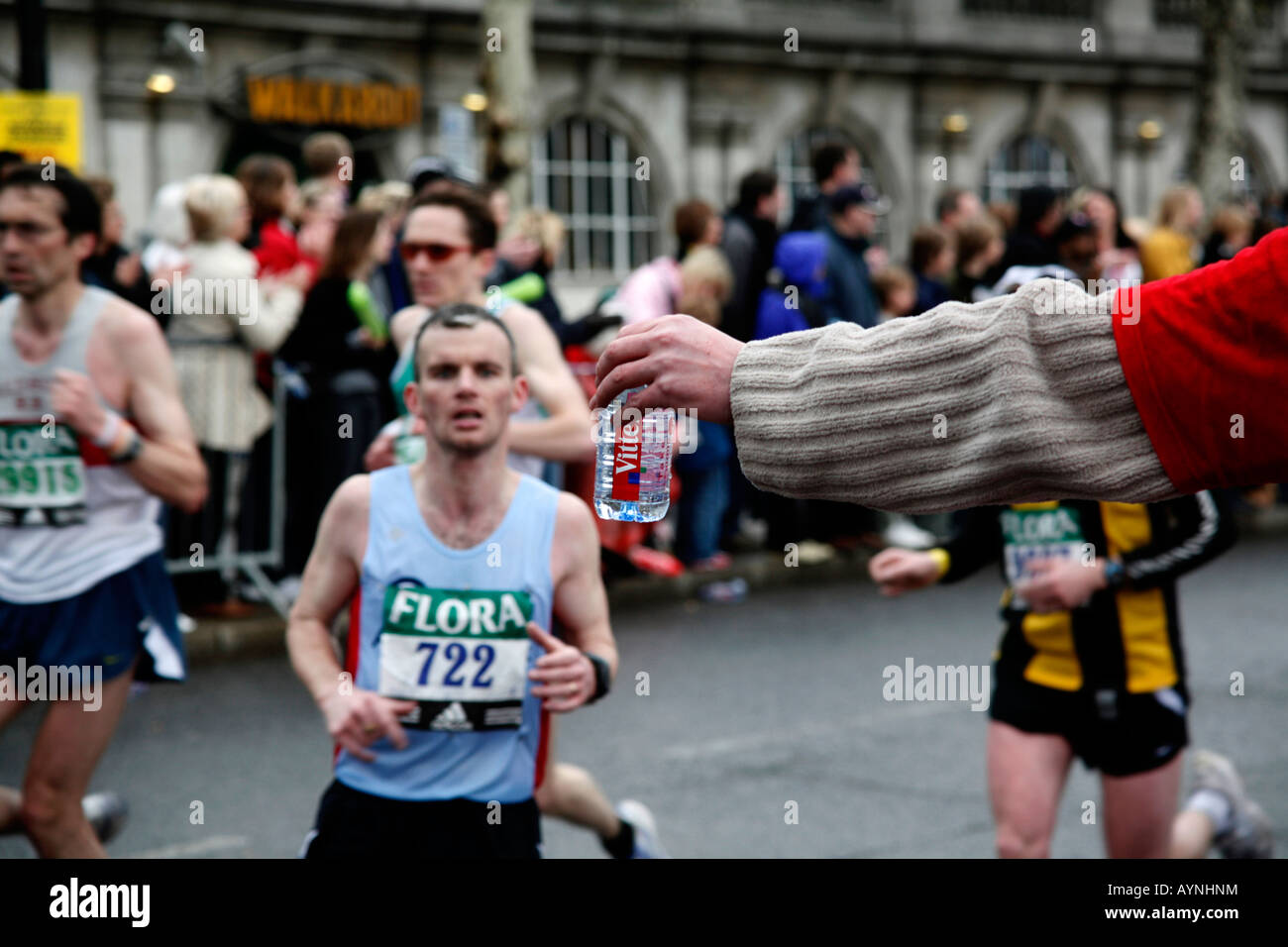 A hand offering bottled water to runners in the London Marathon Stock ...