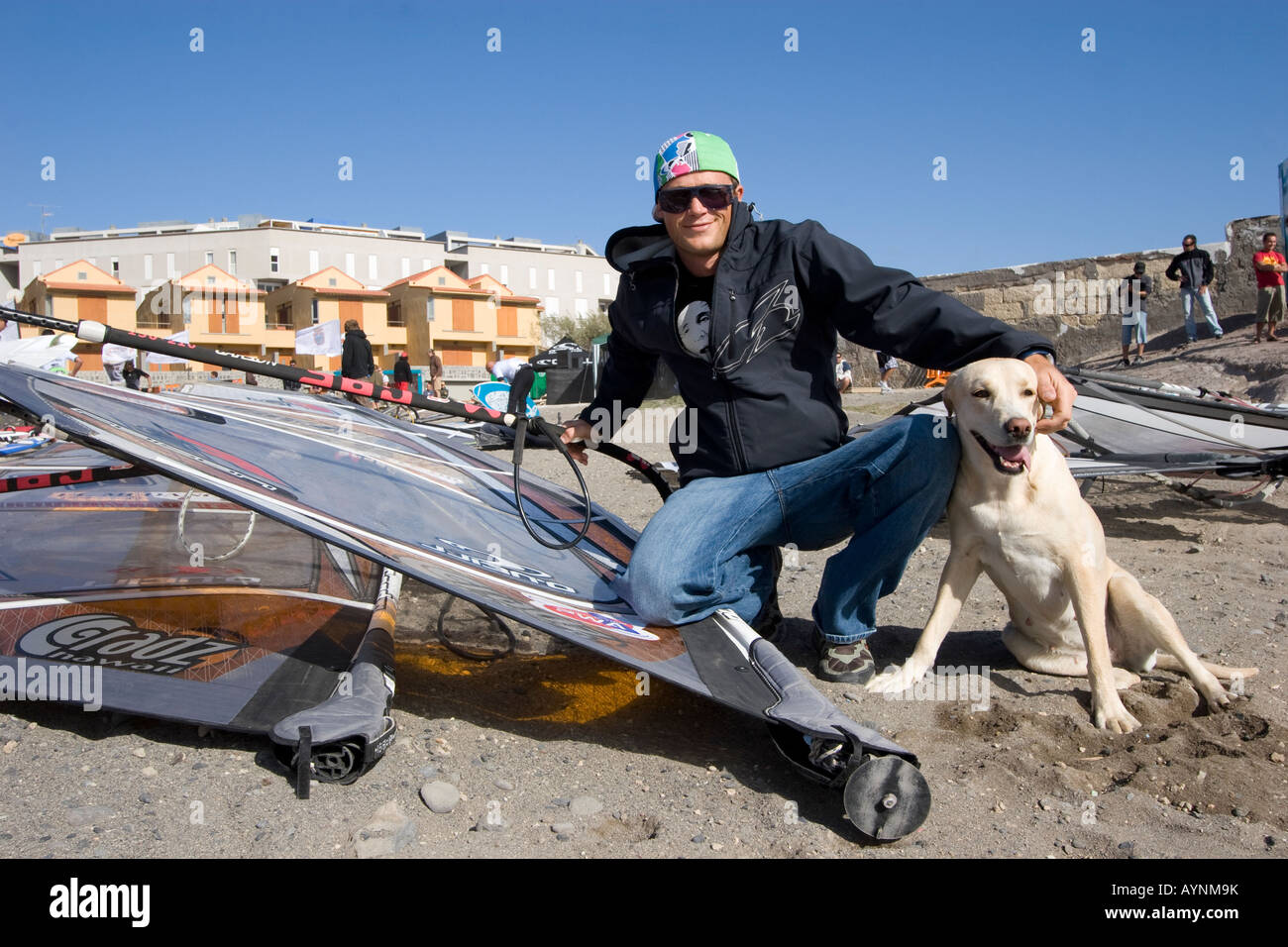 A windsurfing champion with a dog sitting next to his windsurfing ...