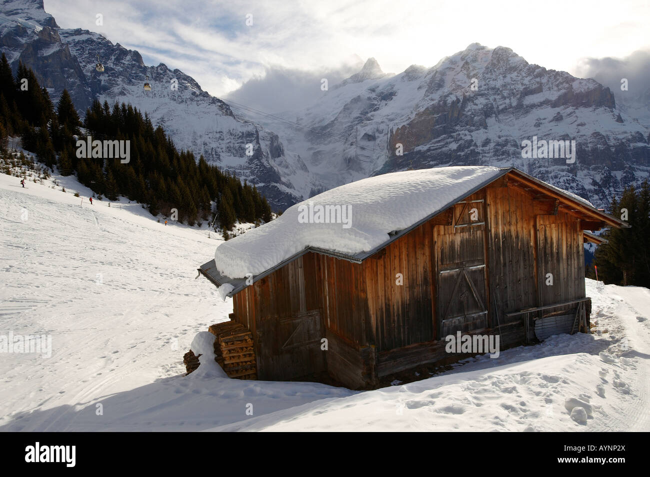 Traditional Swiss wooden hut in snow - with the Schreckhorn mountain ...