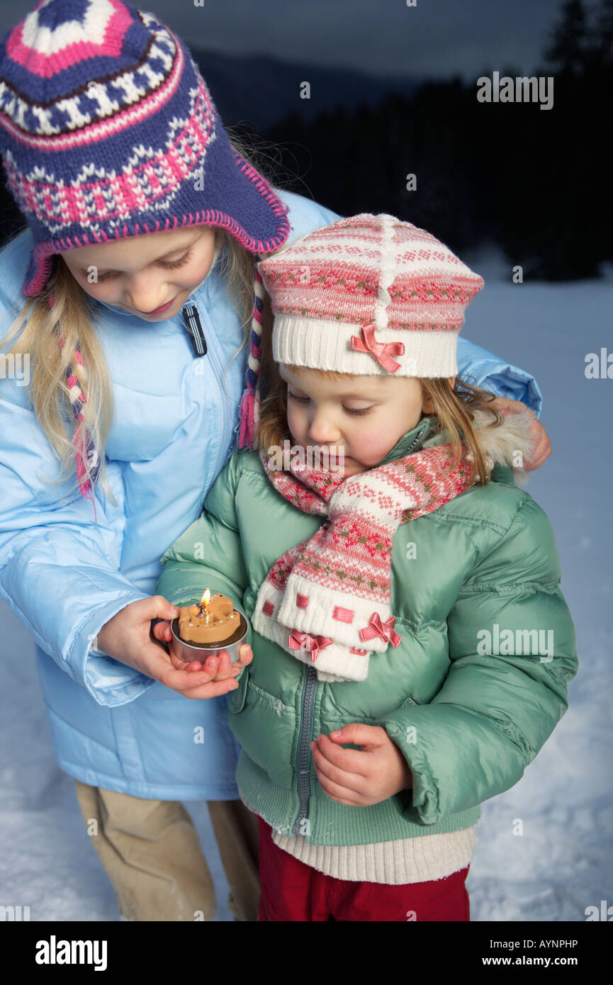Two girls wearing warm clothing holding a burning candle Stock Photo ...
