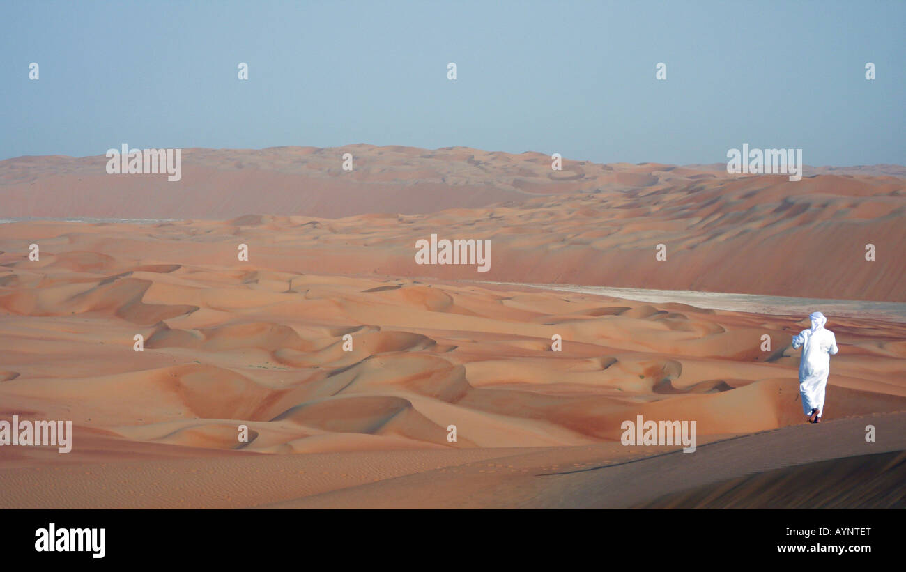 An Emirati guide in traditional dress walks in the desert in Liwa ...