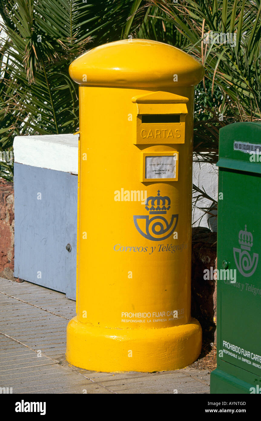 A yellow post box adorned with the silver logo of the mail company set ...