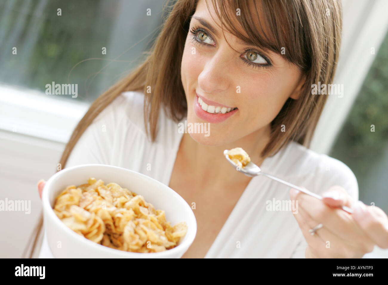 Brunette girl eating Cornflakes cereal Stock Photo - Alamy