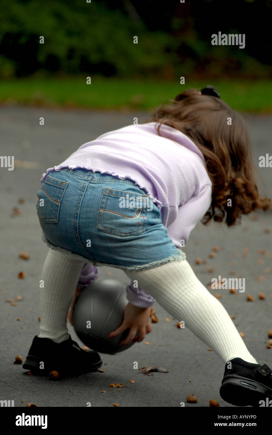 Backside view of a three year old girl picking up a basketball Stock ...