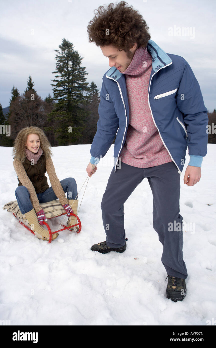 Young man pulling a sled with a blonde woman sitting on it Stock Photo ...