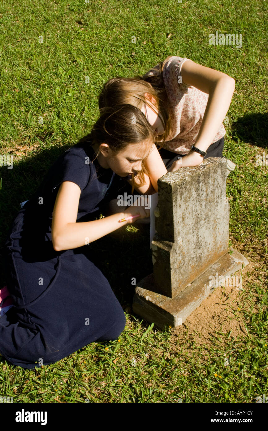 Children in cemetery rubbing grave stone Stock Photo - Alamy