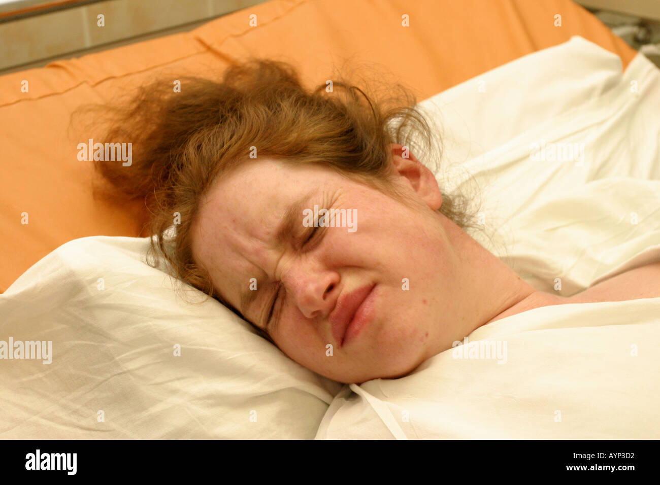 Young pregnant woman in later stages of labour (labor) in pain, in ...