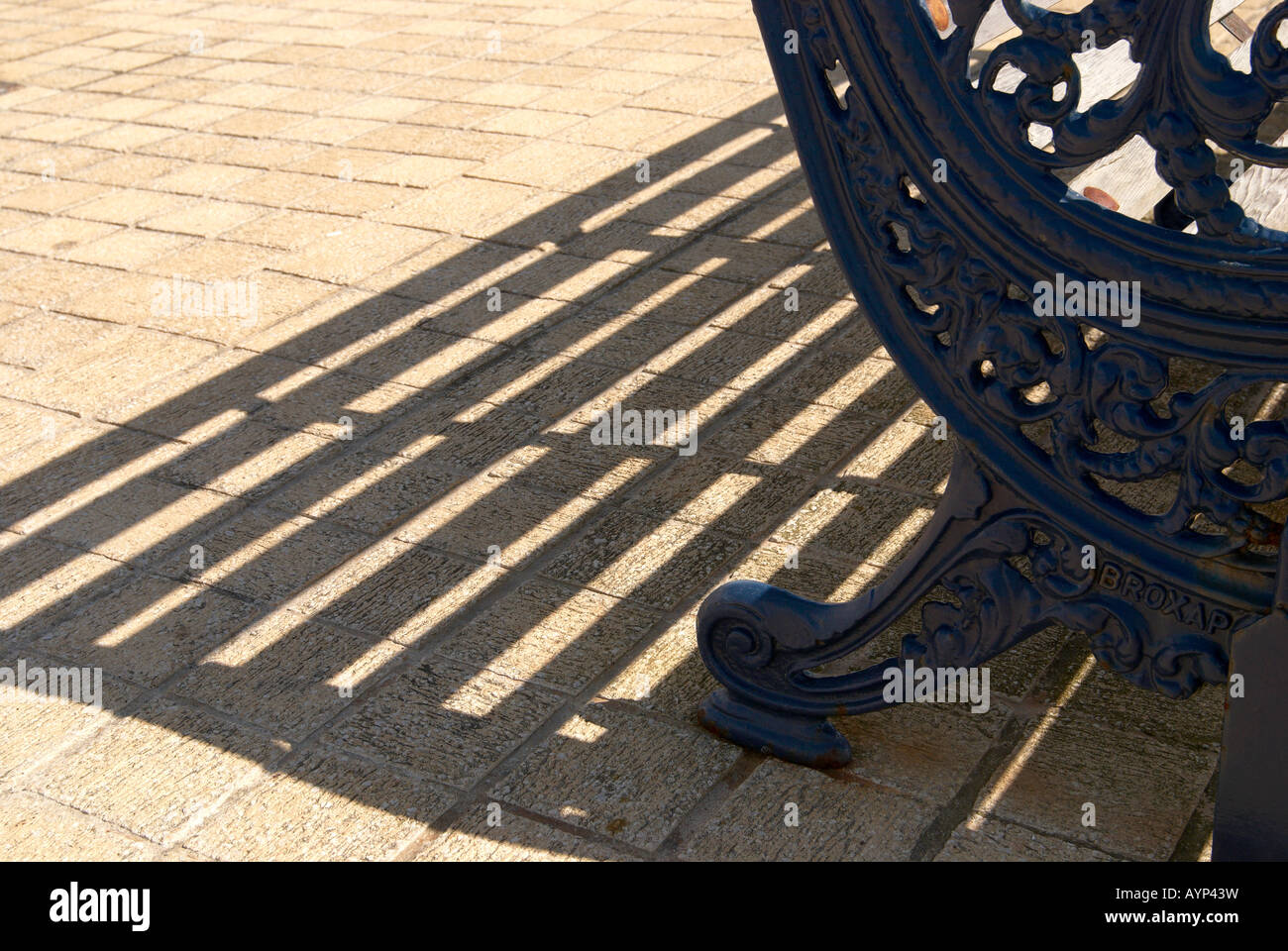 Shadow cast by sun shining through the slates of a bench with a cast ...