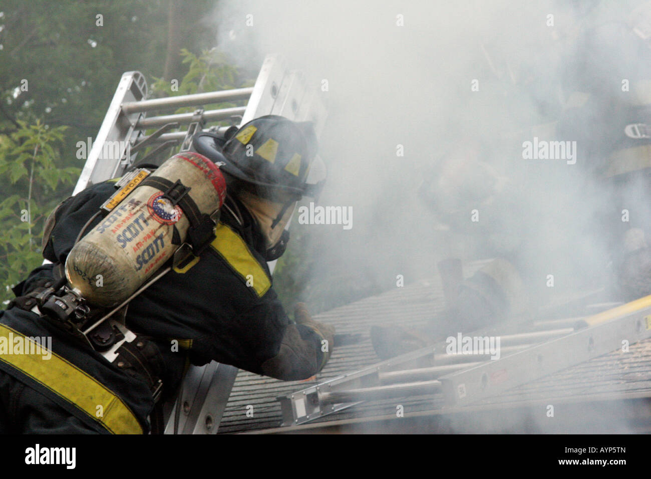 A firefighter on the ladder reaching to another firefighter on the roof ...