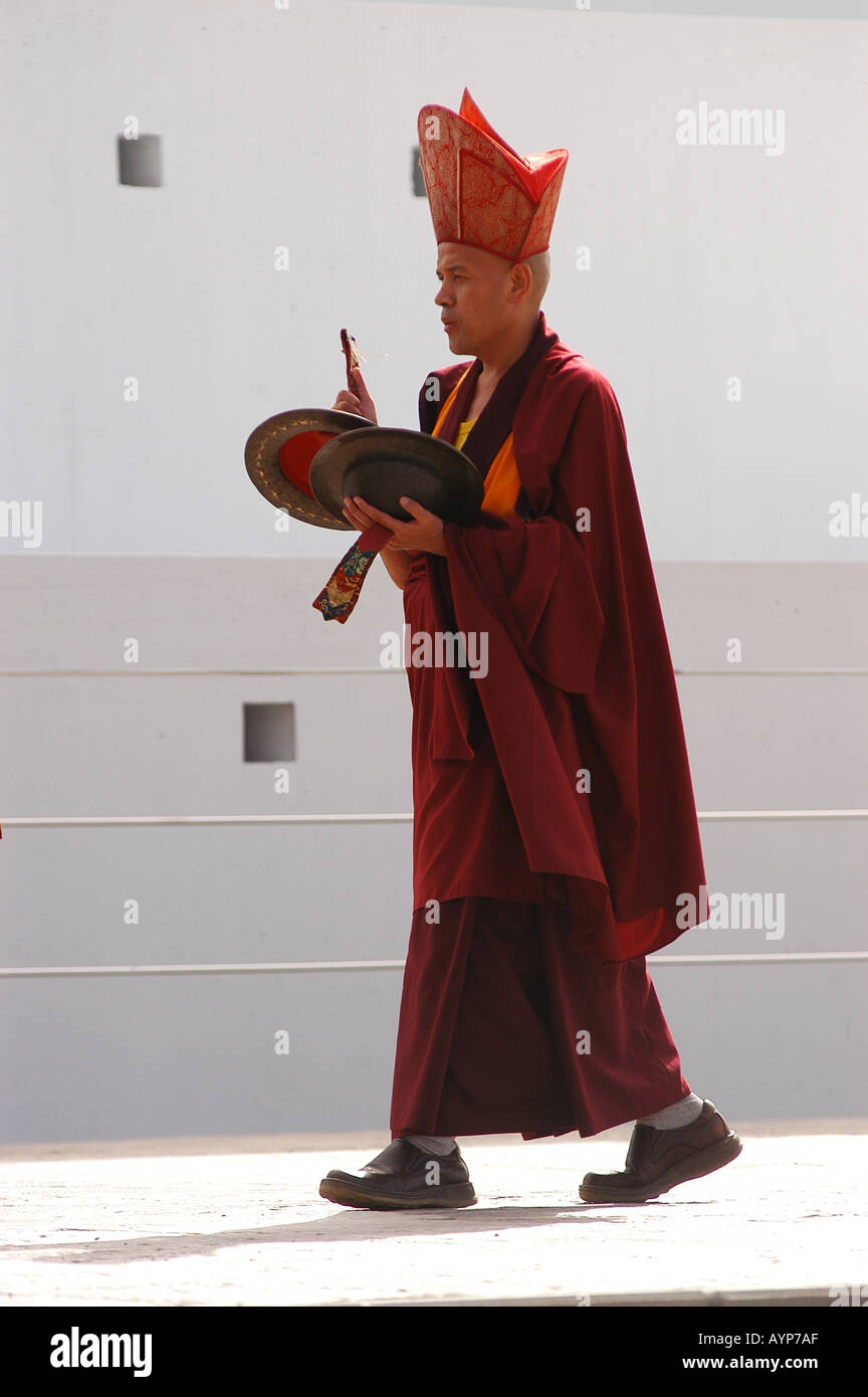 Tibetan buddhist monks in traditional maroon robes and ceremonial hats ...