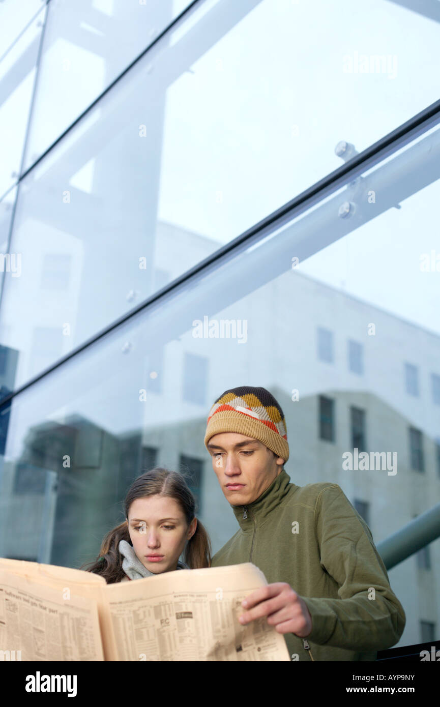 Young couple reading a newspaper Stock Photo - Alamy