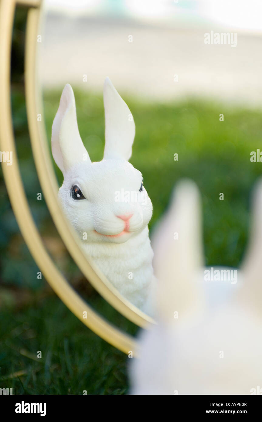 A surreal scene of a toy white rabbit, looking at itself in the mirror ...
