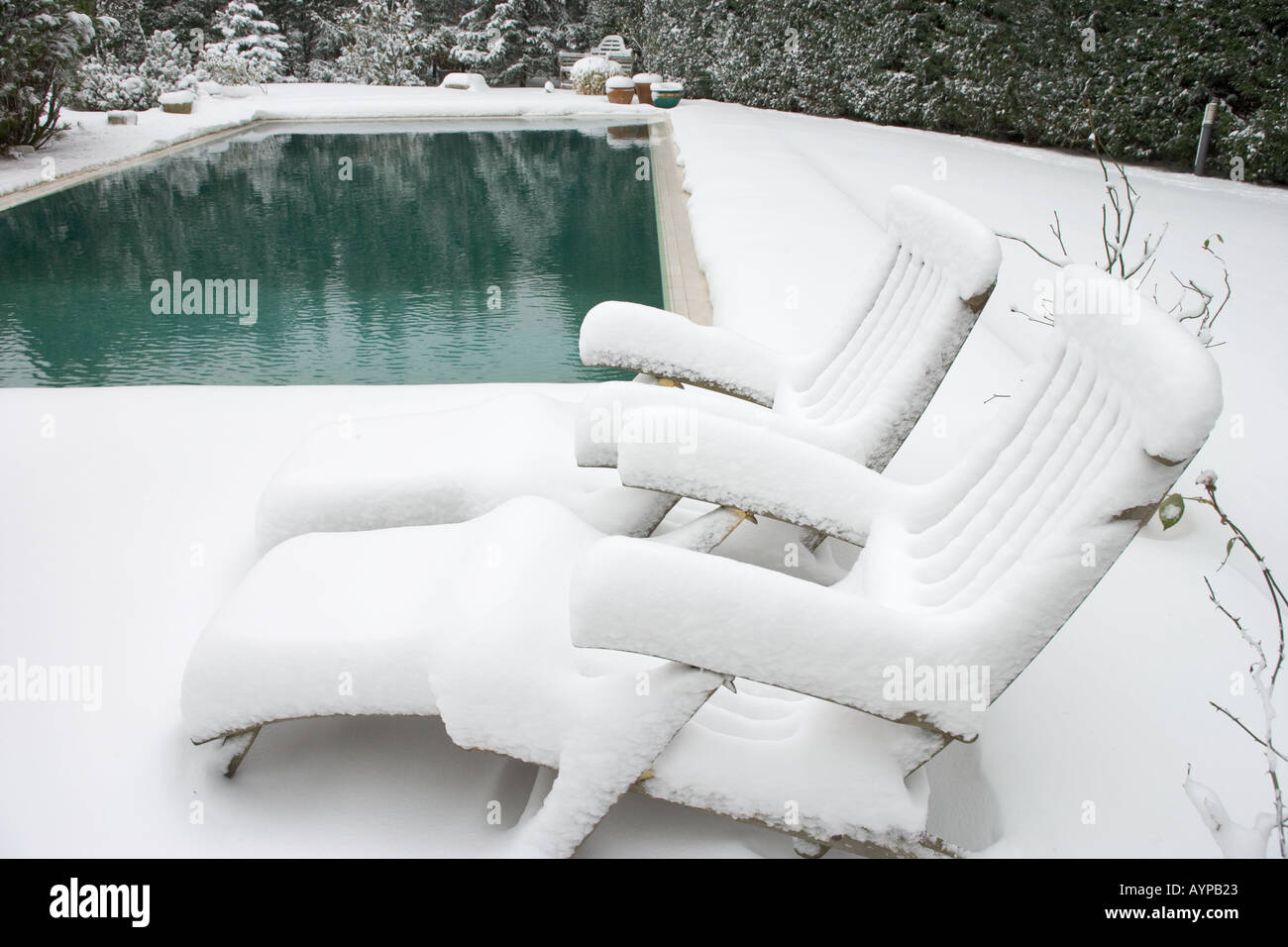 Couple of chaises longues under snow by a swimming pool Stock Photo - Alamy
