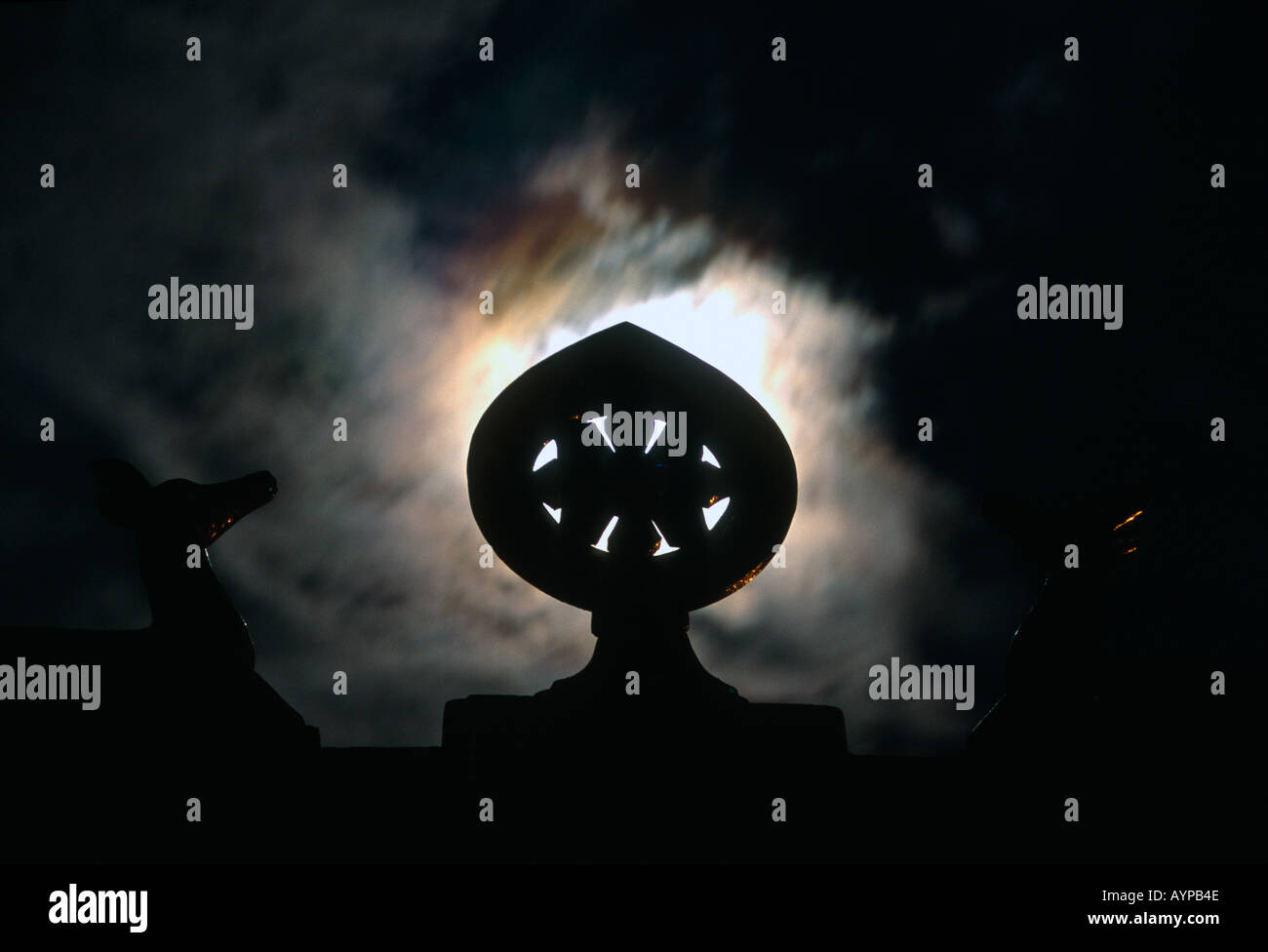 Silhouette of a Buddhist wheel of Dharma backlit by a bright full moon ...