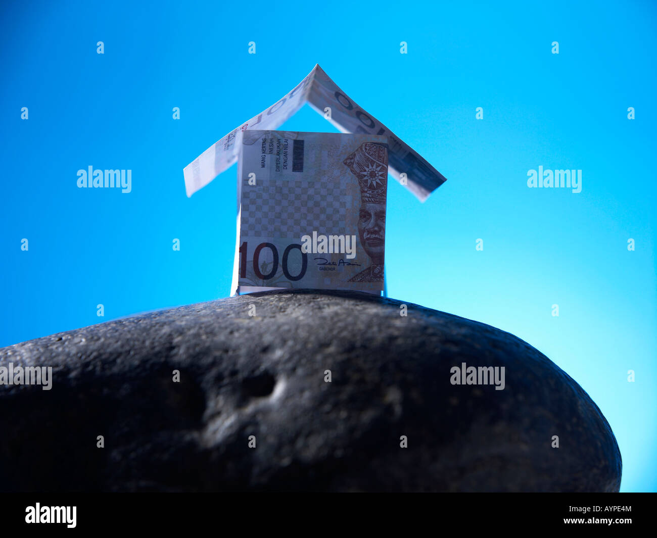 Folded ringgit malaysia into a house, place on a rock Stock Photo - Alamy