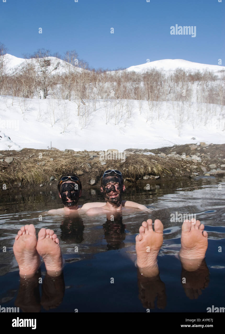 Two people soaking in natural outdoor hot spring with mineral mud face ...