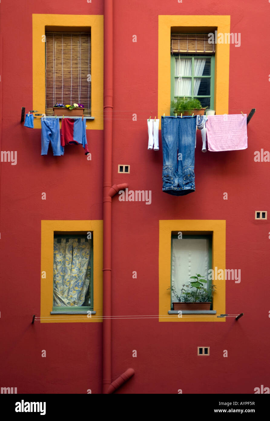 Clothes drying outside four windows of a pastel colored building in ...