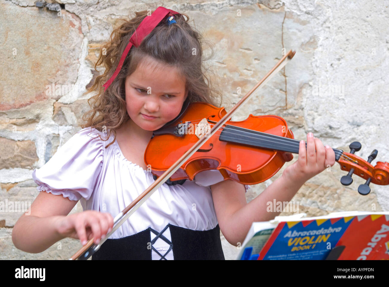 Young girl busking with a violin at a colonial market day at the Female ...