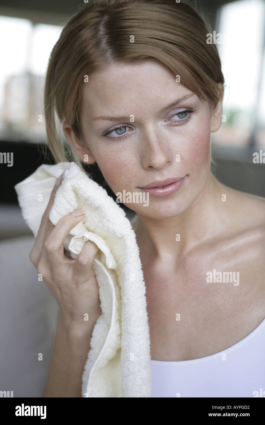 A blonde woman wiping her face with a towel Stock Photo - Alamy