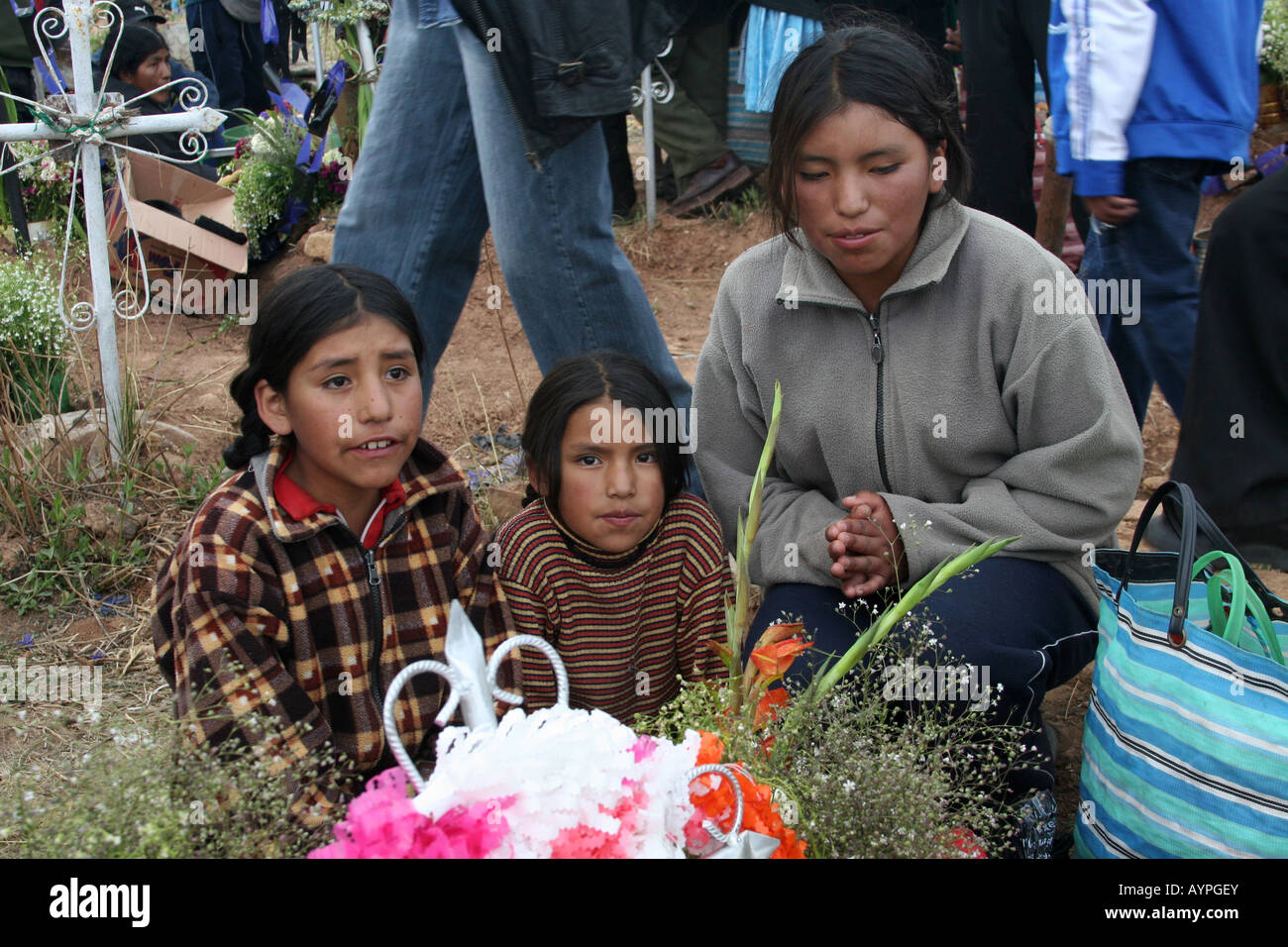Three young girls praying in front of a grave during Todos Santos in ...
