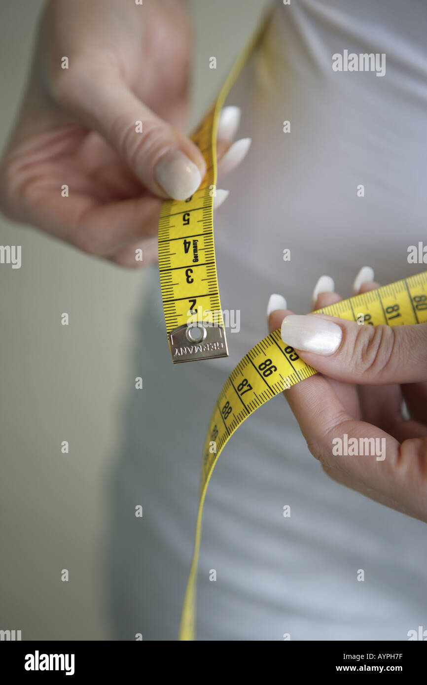 A midsection of a woman holding a measuring tape round her waist Stock ...