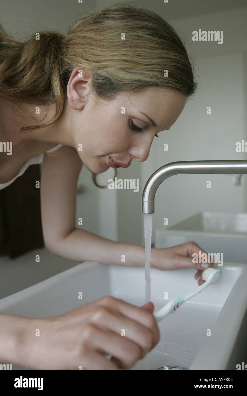 A blonde woman brushing her teeth Stock Photo - Alamy