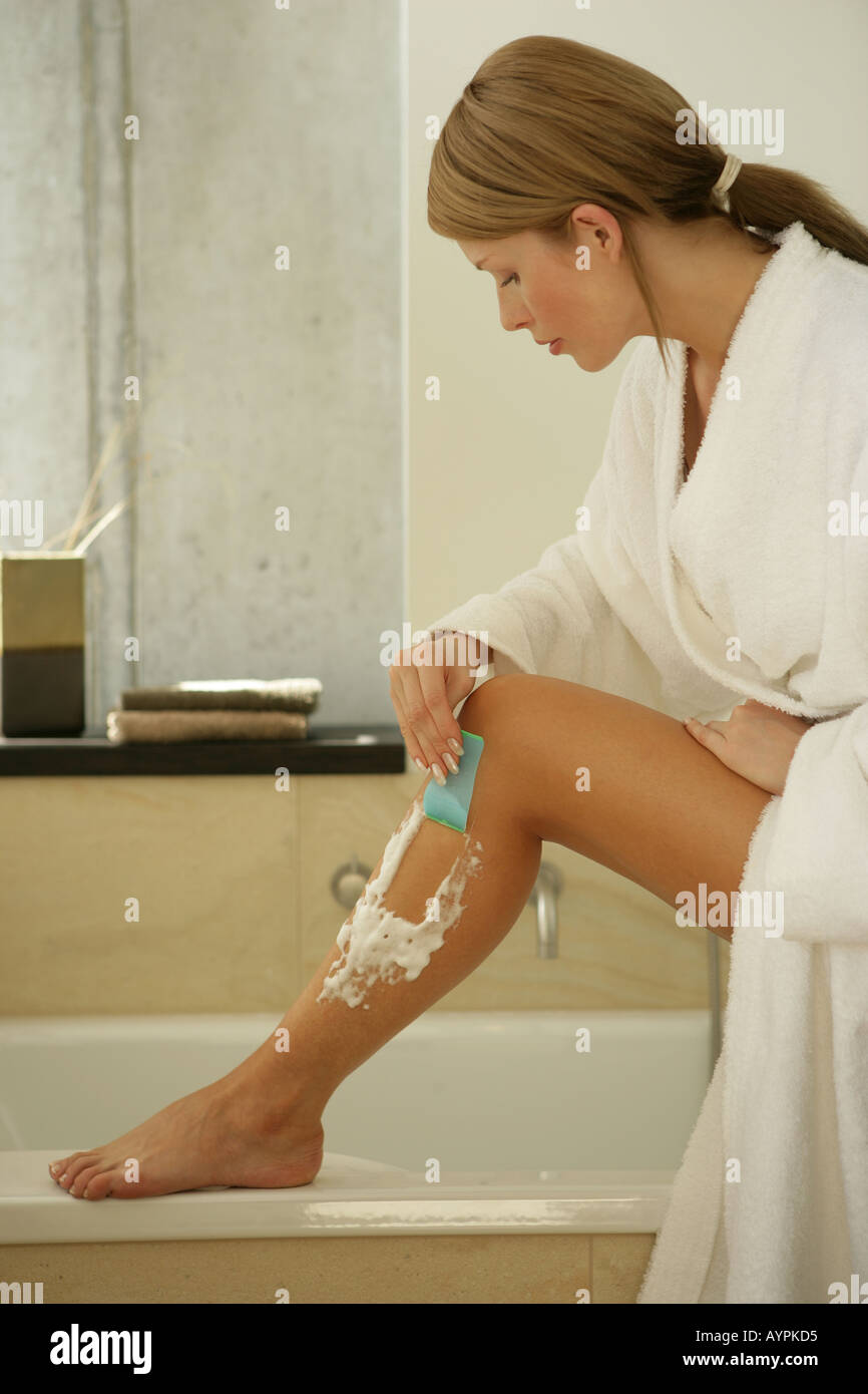 A blonde woman using an epilator on her leg Stock Photo - Alamy