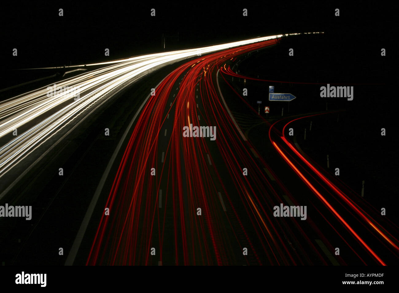 Large group of cars speed along highway as the trails are seen at night ...