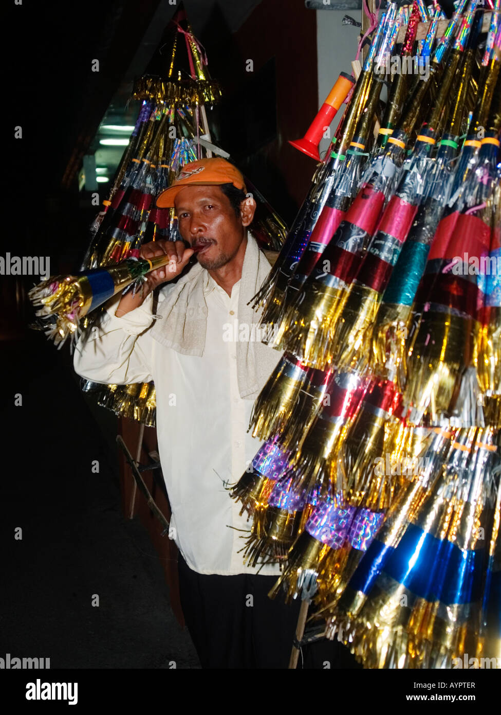 Local man selling brightly coloured paper trumpets for new year ...