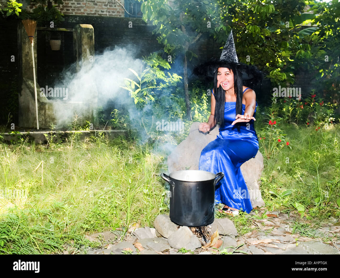 Young,pretty witch in blue dress and pointed hat casts spells in a ...