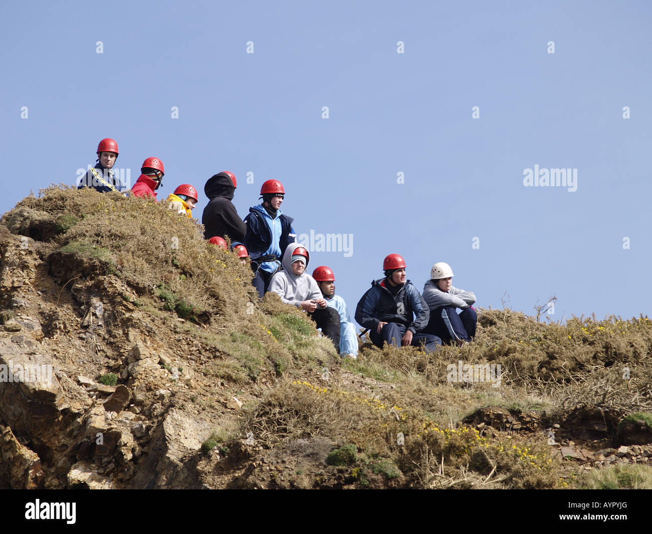 A group of teenage boys learning to abseil watching and waiting their ...