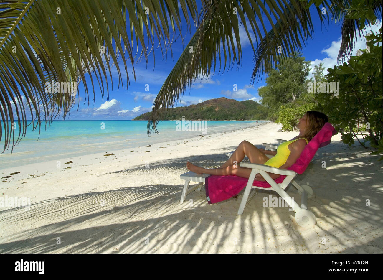 Young woman on deck chair, sleeping under palm trees, Praslin Island ...