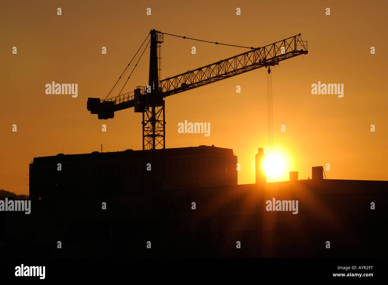 Construction crane at a building site, setting sun Stock Photo - Alamy