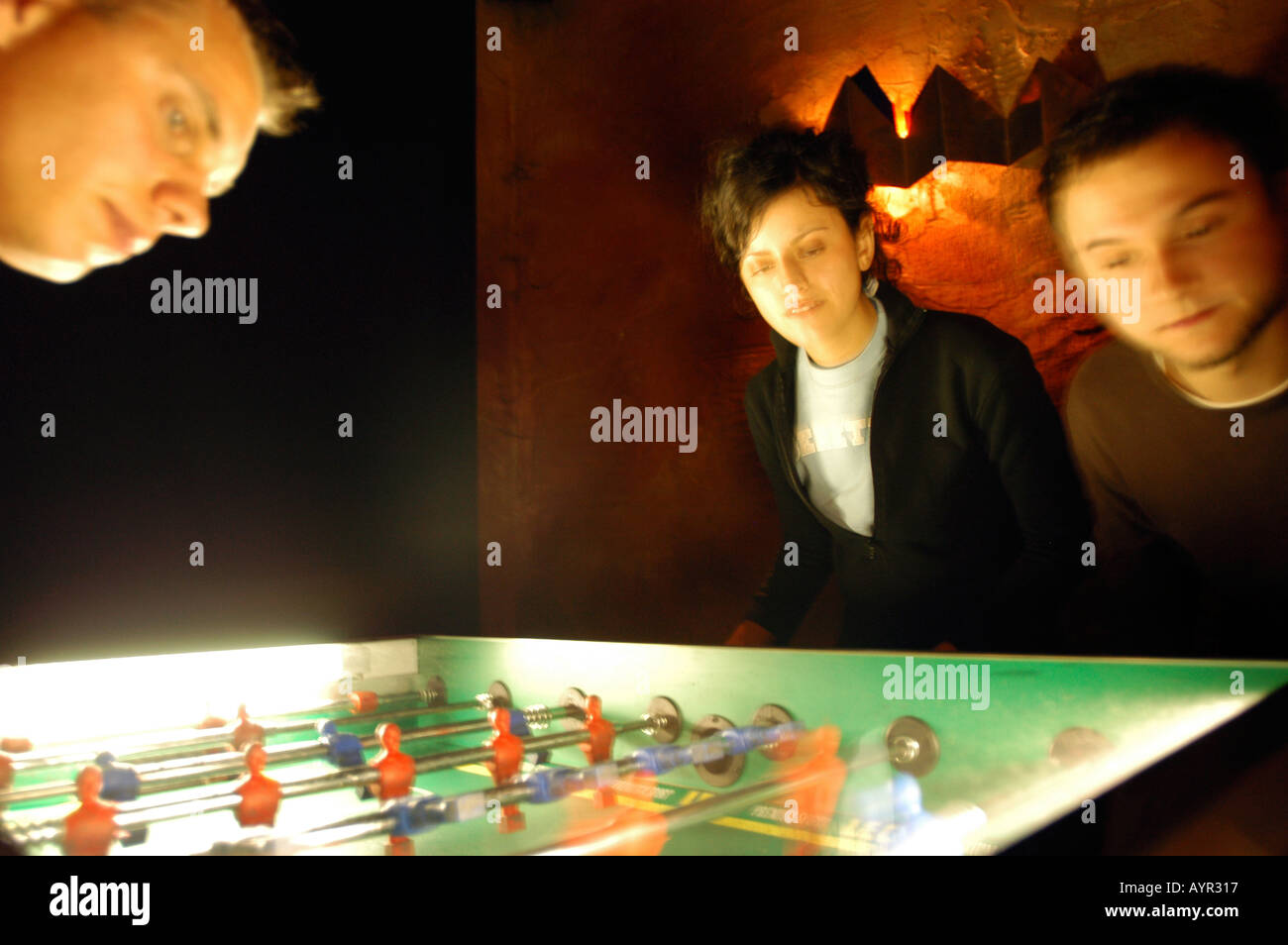 Two men and woman playing table soccer in pub Stock Photo - Alamy